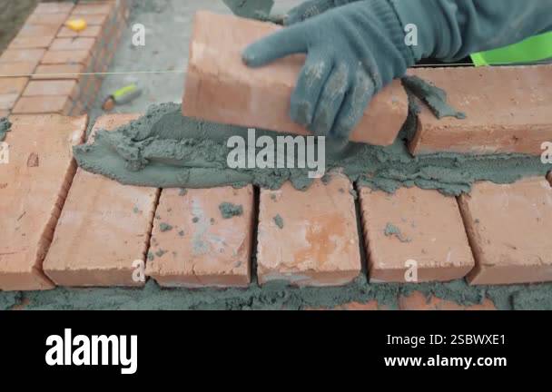 Bricklayer placing bricks with mortar during construction, Worker using ...
