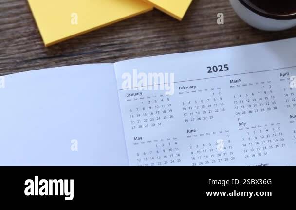 2025 new year calendar notebook planner on wooden desk with cup of ...