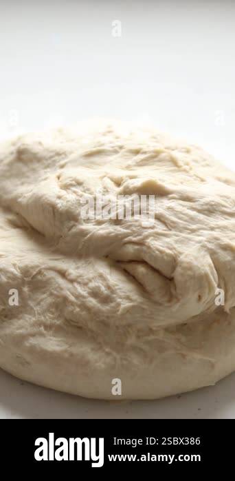 Wheat flour is falling on homemade bread dough. Vertical video. Close ...