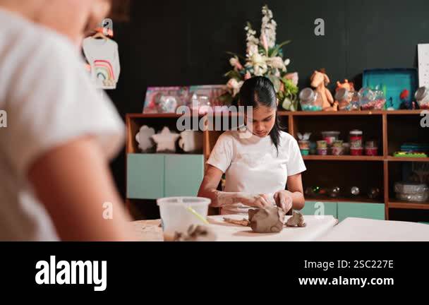 Attractive caucasian girl modeling cup of clay at pottery workshop ...
