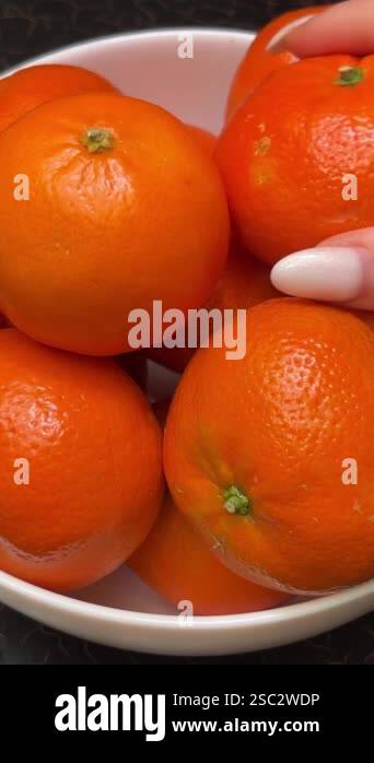 bright oranges tangerines stand in a white plate on a black table a ...