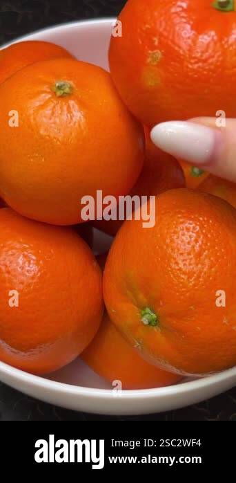 bright oranges tangerines stand in a white plate on a black table a ...