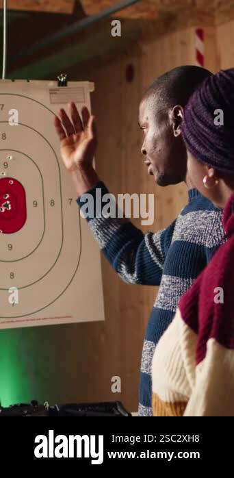 Vertical video Shooting gallery instructor explaining bullseye scoring ...