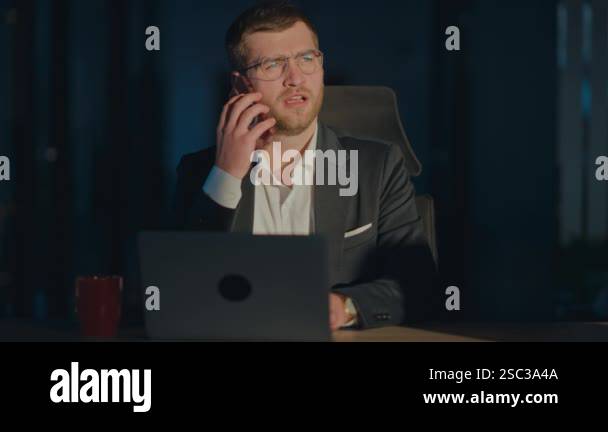 Businessman in a suit, engaged in a phone call at night, working on a ...