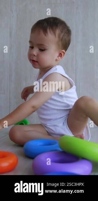 Adorable active toddler disassembling toy pyramid. Kid cheerfully takes ...
