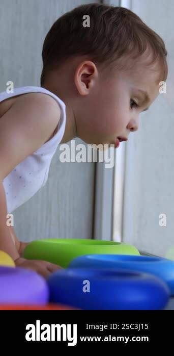 Cute Caucasian child sits on the floor near panoramic window. Kid looks ...