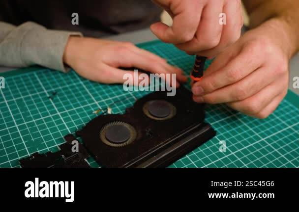 Unrecognizable hands securing laptop cooling system, tightening screws ...