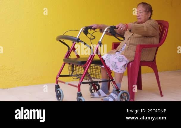 Elderly woman standing up leaning on walker and starting to walk ...