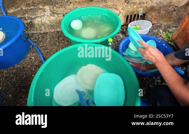 Person scrubbing and rinsing dishes in buckets outside Stock Video ...