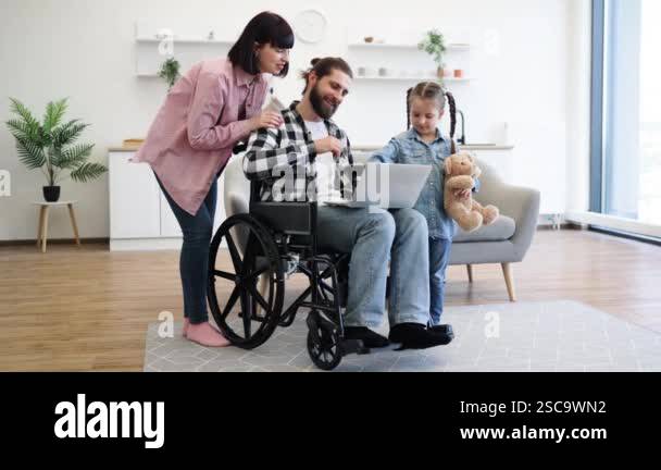 Caucasian family in modern kitchen, mother, father in wheelchair with ...