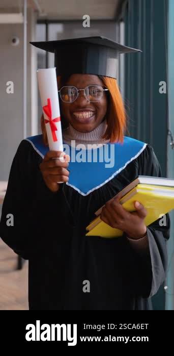 A determined graduate in a black cap and gown walks indoors while ...