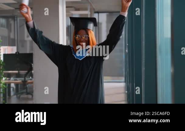 Excited African American female graduate wearing a cap and gown ...