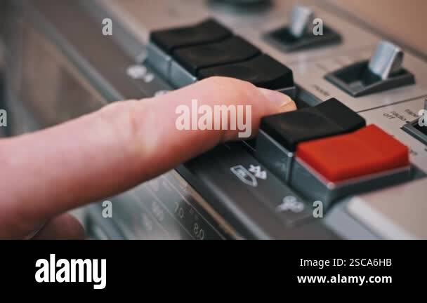 Finger presses the play button on a retro audio device, focusing on the mechanical action ...