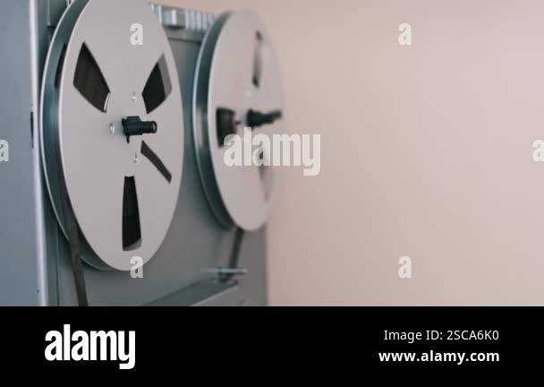 A retro reel-to-reel tape player is shown with both reels spinning ...