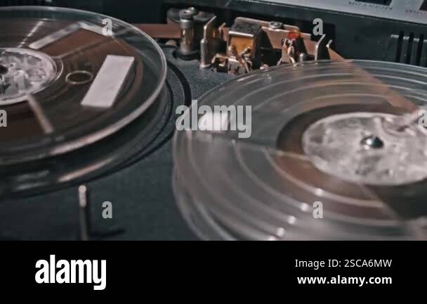 Close-up of a vintage reel-to-reel tape recorder with transparent ...