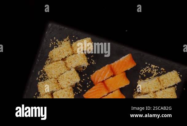 A sushi platter featuring sesame-coated rolls and fresh salmon pieces ...