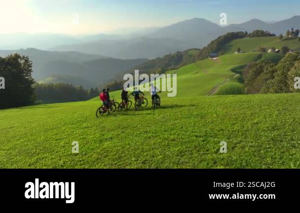 AERIAL: Cycling friend taking a break on a hilltop, surrounded by ...