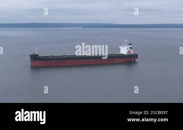 Aerial view of a stationary cargo ship with a red hull and white ...