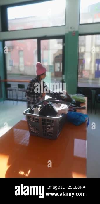 A person sorting through a large pile of laundry in a bright indoor ...