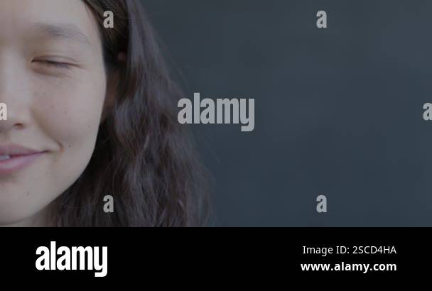 Close-up portrait of happy Asian woman half face smiling looking at ...