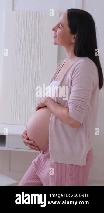 Happy Caucasian middle aged woman stroking a pregnant belly at home ...