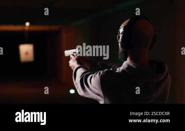Shooting gallery customer using pistol to hit targets, wearing ...