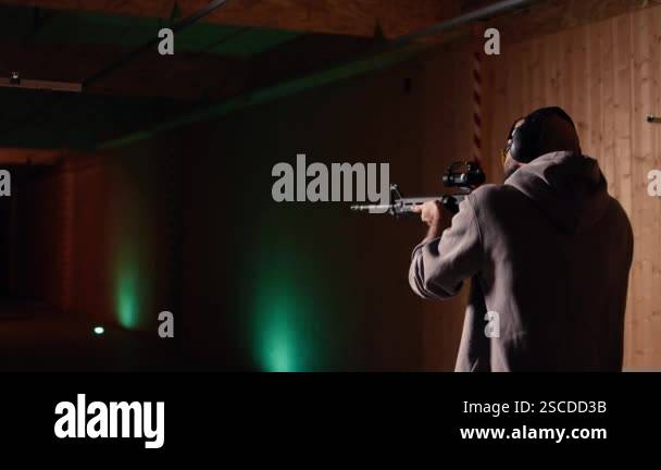 Shooting gallery client using assault rifle to hit targets, wearing ...