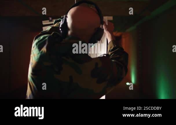 Man in firing range shooting targets with pistol, wearing earmuffs to ...