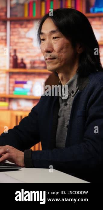 Vertical video Portrait of smiling senior engineer coding advanced AI algorithm in startup ...