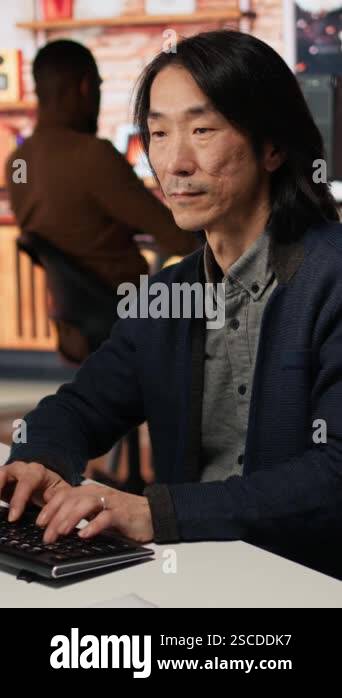 Vertical video Portrait of smiling senior engineer coding advanced AI algorithm in startup ...