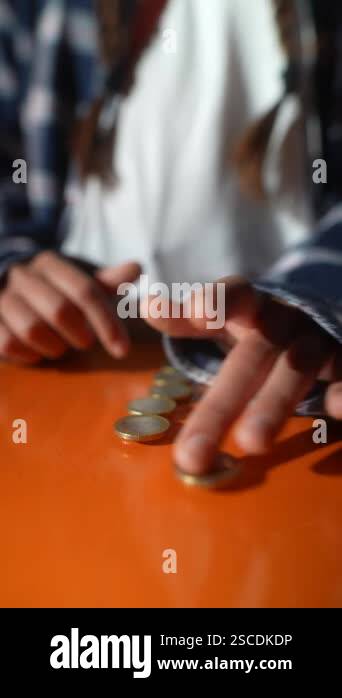 A focused shot shows hands arranging coins neatly, highlighting ...