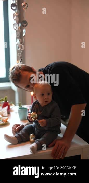 A delighted parent and their baby are joyfully decorating together for ...
