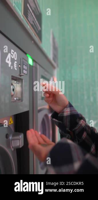 A person is carefully inserting coins into a vending machine in order ...