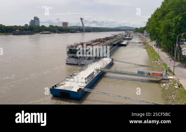 A river cruise ship docked along the shore, with a modern bridge and ...