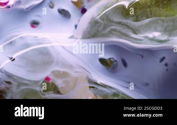 Wavy ink. Icy leaves. Liquid white paint with colored glitter pour ...