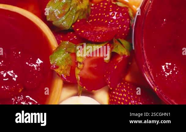 A close-up of fresh strawberries and strawberry sauce, with two bowls ...
