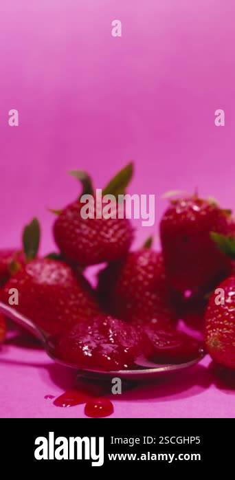 A close-up of fresh strawberries with a spoon dripping strawberry syrup ...