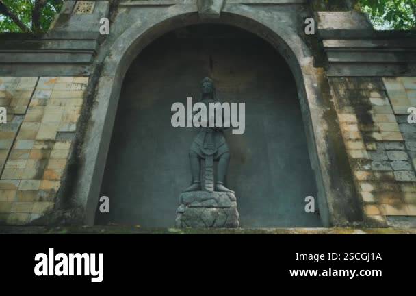 A stone statue of a warrior stands prominently in an archway ...