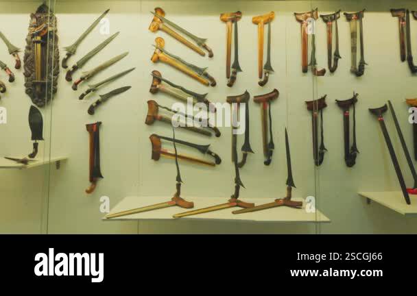 A display of various traditional swords and daggers arranged on a wall ...