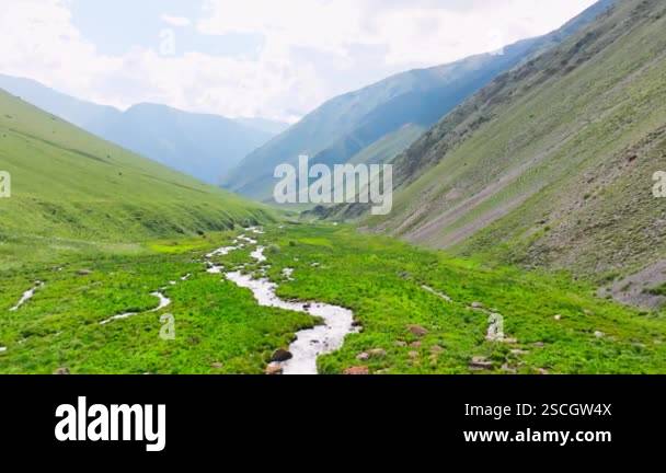 Green mountain gorge with grass slopes and braided river at sunny day ...