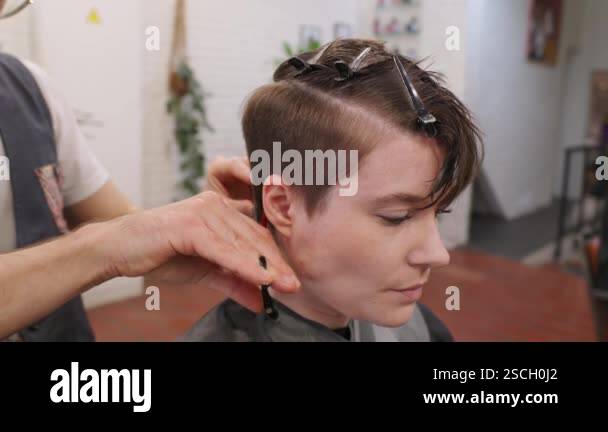 Professional hairdresser preparing female clients short hair with ...