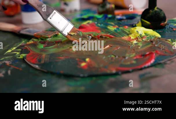 Closeup of a detailed paintbrush mixing vibrant colors on an artists ...