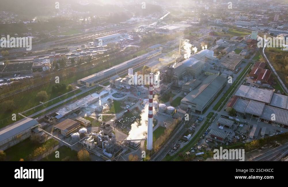 Aerial: Flying in front of factory with big chimneys with smoke coming ...