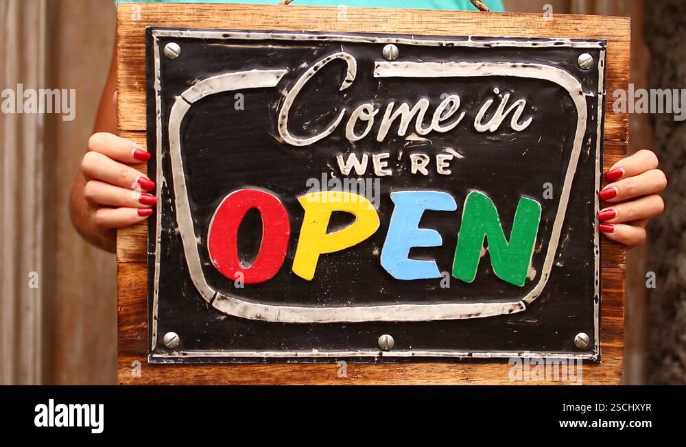 Open sign board in a woman hands on a tropical nature background ...