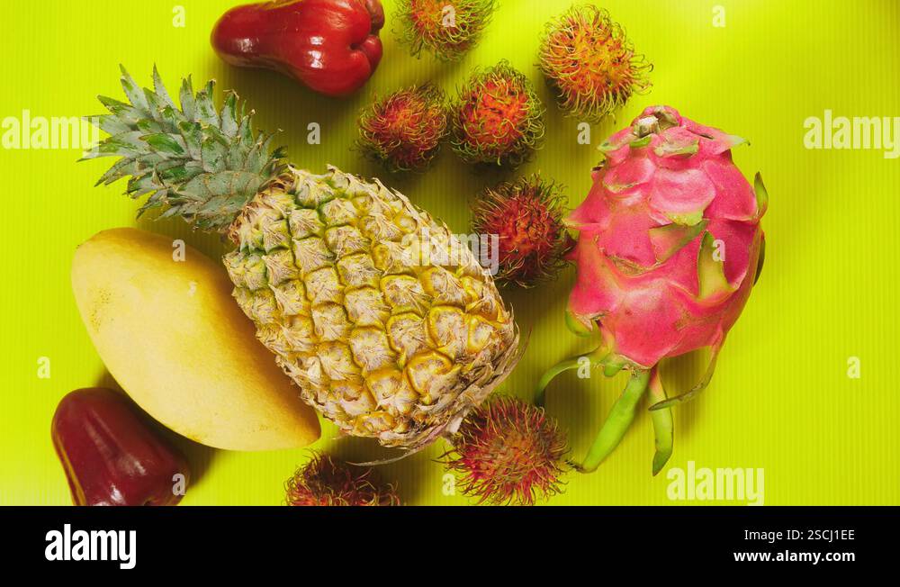 hands take away tropical fruits with a bright yellow background ...