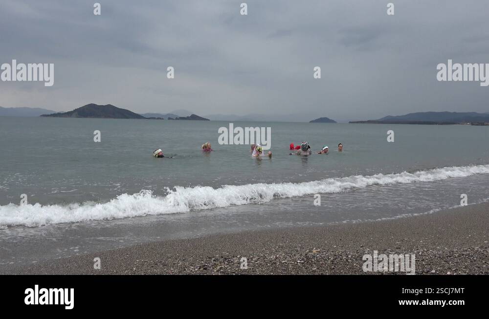Zoom in a group of fancy dressed people swimming in the chilly winter ...