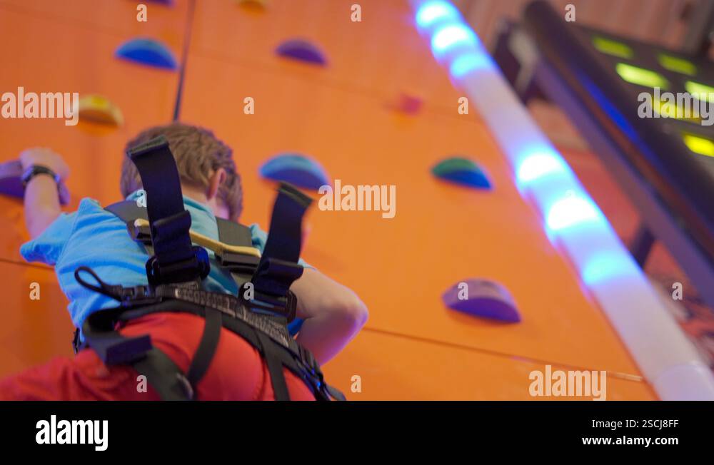 Boy climbing challenge on indoor climbing wall at trampoline park Stock ...