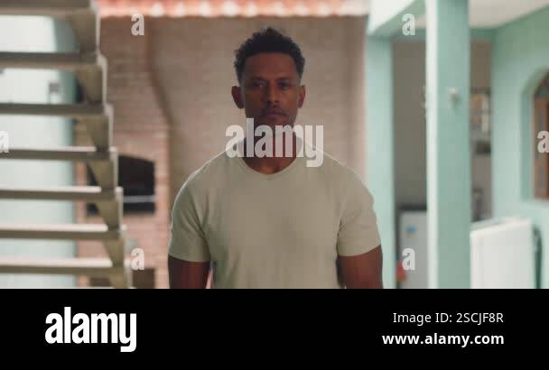 Man of African descent standing indoors with neutral expression, casual ...