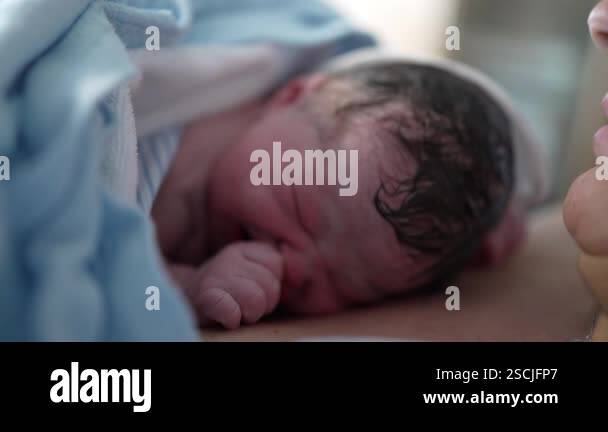 Close-up of newborn baby right after birth resting on mother's chest ...