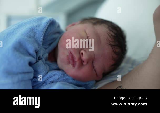 Close-up of newborn baby's face resting on mother's chest during his ...